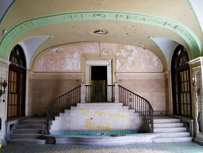 Twin staircases curve upward beneath a painted arch, creating symmetry that still takes your breath away.