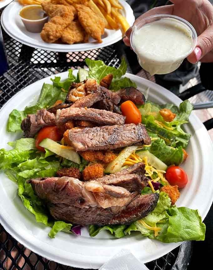 Tender steak slices crown this vibrant salad while chicken tenders wait nearby, doubling down on protein perfection.