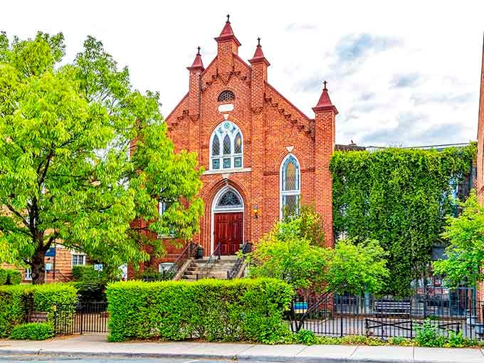 A stunning Gothic Revival brick church nestled among lush greenery, reminding you that beauty here comes in many forms.