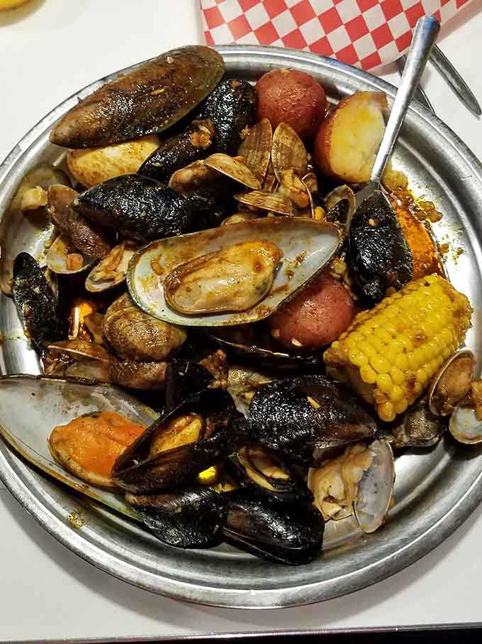 Mussels and clams piled high on a metal platter, soaking up savory sauces like tiny flavor sponges.