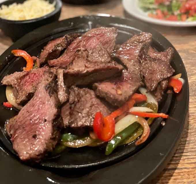 Sizzling steak sliced thick and nestled with peppers creates a presentation worthy of applause and appetite.