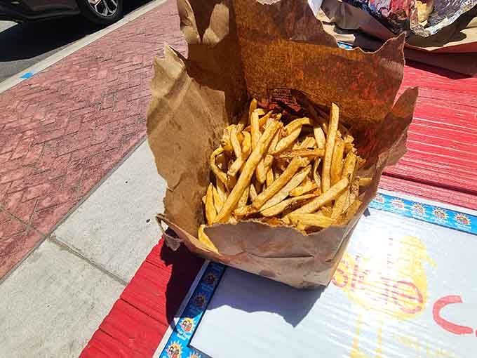 Hand-cut fries piled high in a paper bag, because sometimes presentation means knowing when to get out of the way.