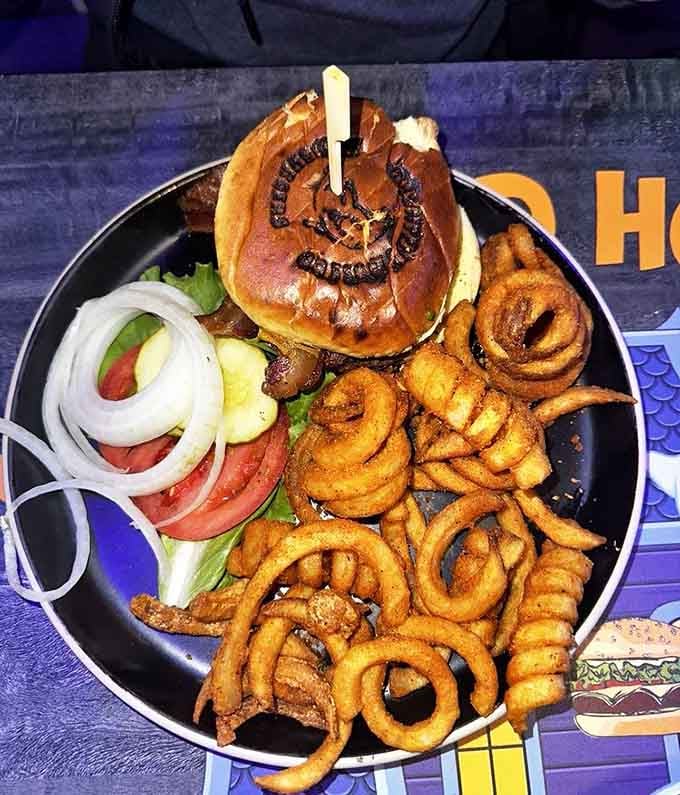 This burger comes with enough toppings to require architectural engineering, served alongside perfectly golden onion rings for good measure.