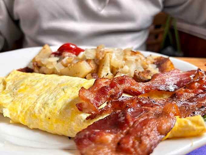 Bacon cooked to crispy perfection alongside an omelet that makes you reconsider every breakfast choice you've ever made before.