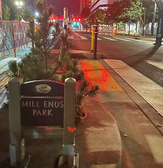 At night, Mill Ends Park glows under streetlights, a small beacon of quirky charm in downtown Portland's urban landscape.