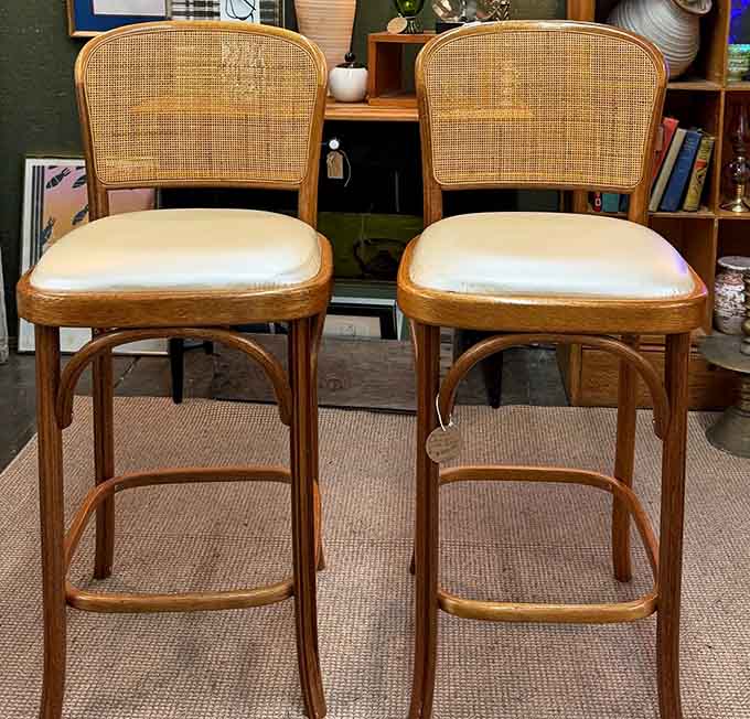Cane-back bar stools with cushions that say "sit down, stay awhile, have a proper drink."
