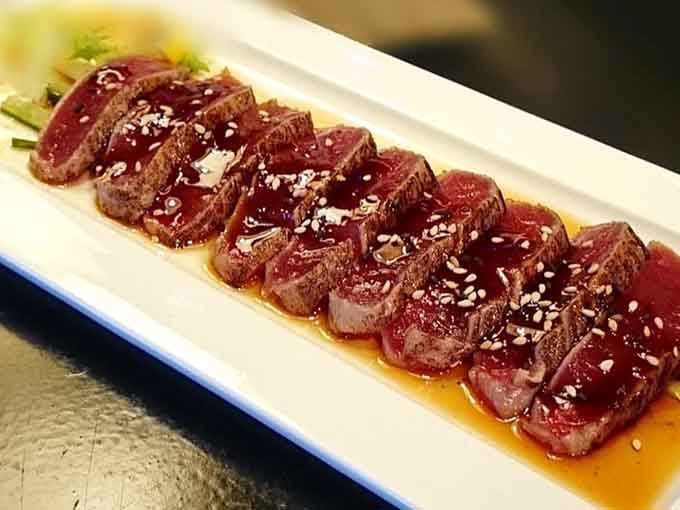 Tuna tataki sliced thin and glistening with sauce, sesame seeds dotting the top like culinary confetti at this flavor party.