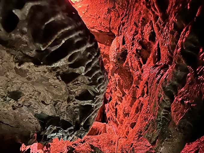 Dramatic red lighting highlights the cave's natural architecture, making geology look downright theatrical and magnificent.