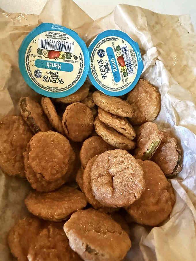 Golden fried pickles paired with ranch dressing offer that perfect tangy crunch that keeps your hand reaching back into the basket.