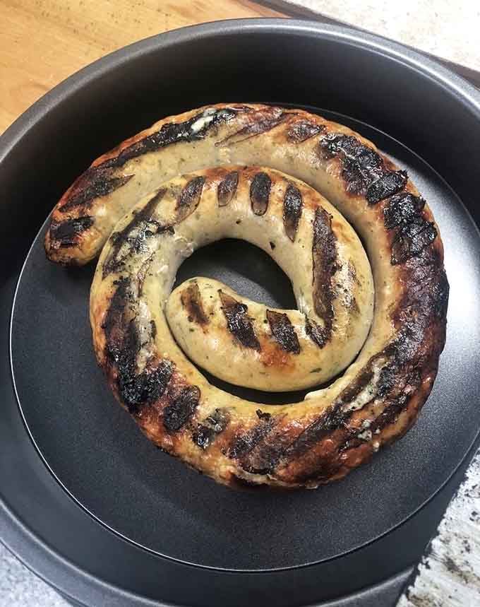 Czech sausage coiled like a delicious spiral, grilled to perfection with char marks that barbecue enthusiasts dream about nightly.