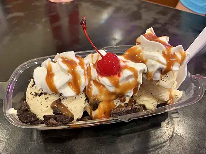 Hot fudge sundae with whipped cream and a cherry delivers childhood memories in every gloriously messy spoonful.