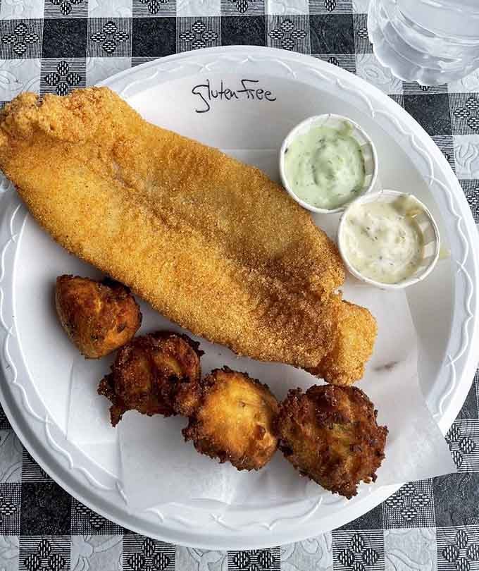 That golden crust on this fish could win beauty pageants, served alongside hush puppies and what appears to be fried potatoes.