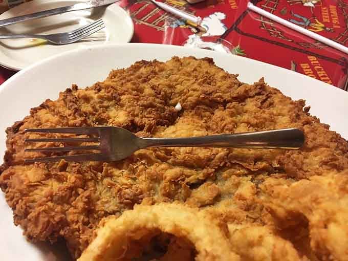 The fork poised over this massive chicken-fried steak captures the moment before pure culinary bliss begins.