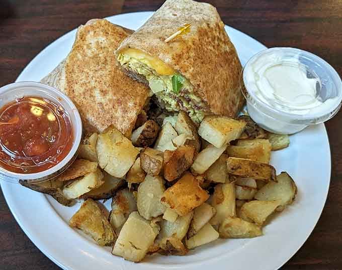A breakfast burrito wrapped tight with golden potatoes on the side, portable perfection meets hearty satisfaction.
