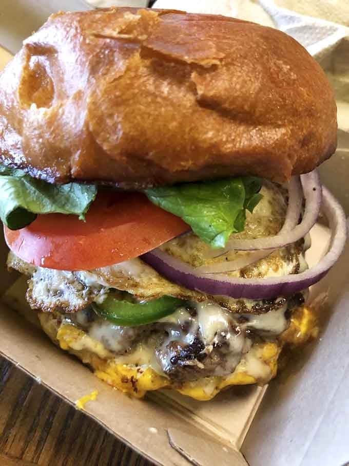 Fresh vegetables layered with precision atop a substantial patty, proving that balance and abundance can coexist beautifully together.