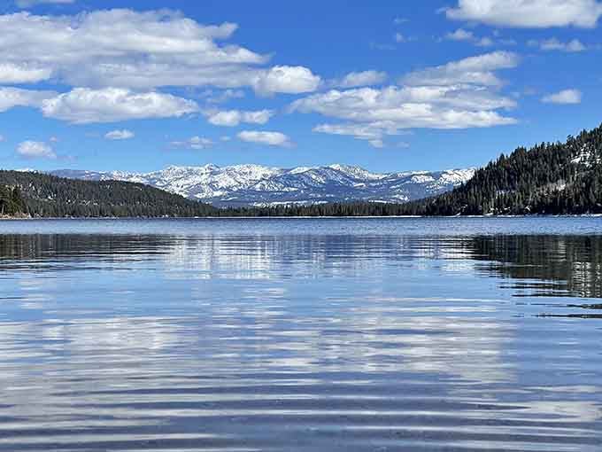 Snow-capped peaks reflected in mirror-smooth water create the kind of view that makes cameras feel inadequate.