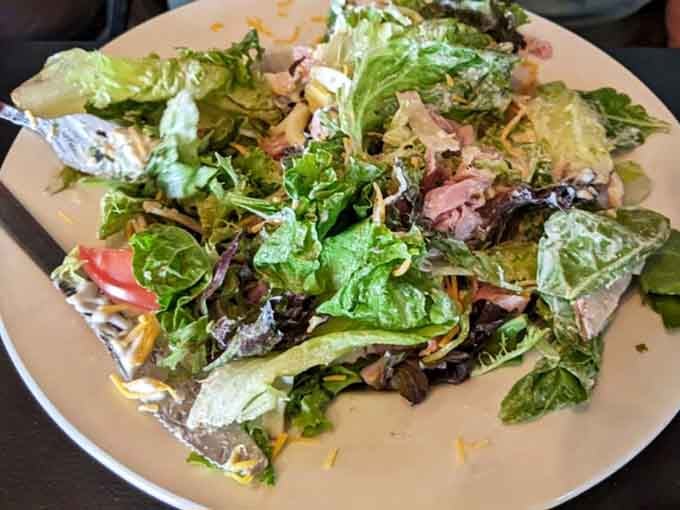 Fresh greens piled high enough to make you feel virtuous before ordering dessert, which you absolutely should do.