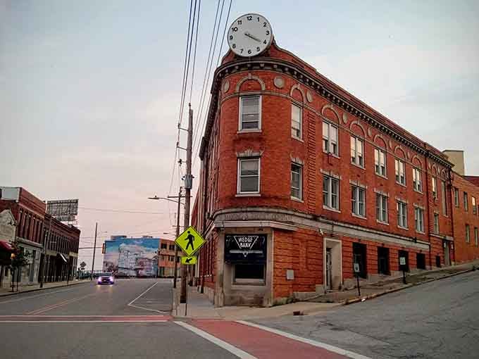 Alton's wedge-shaped brick building wears a giant rooftop clock like a crown, keeping watch over the whole neighborhood at dusk.