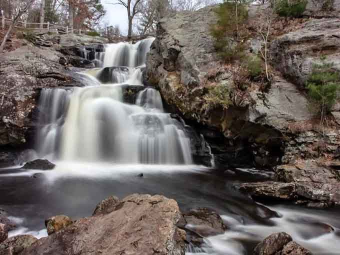 This towering multi-tiered waterfall commands attention as it drops dramatically through the forested landscape below.