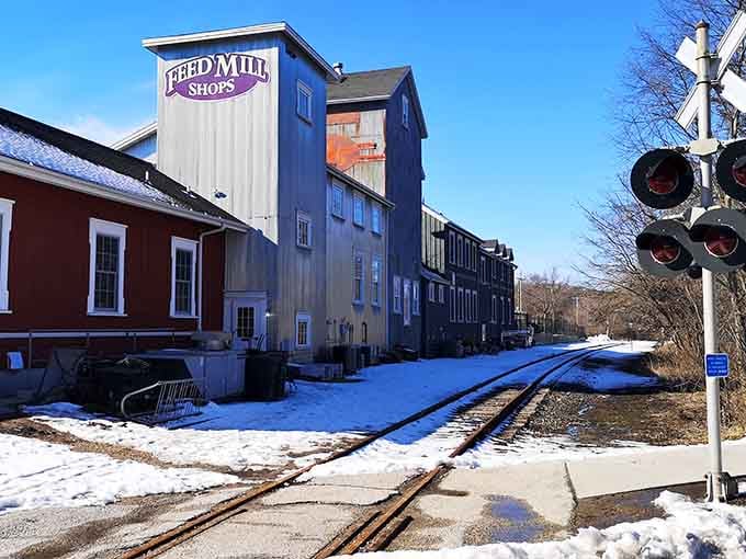 Historic railroad tracks run past the old mill building where industry once thrived and shoppers now explore.