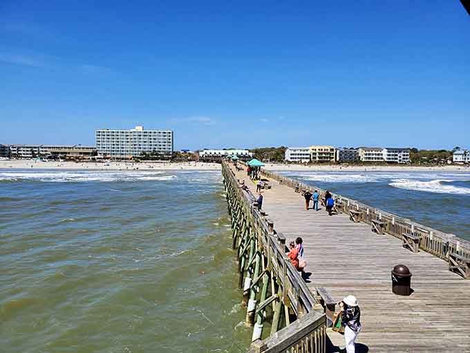 The fishing pier stretches boldly into churning surf, inviting anglers to test their luck against the ocean.