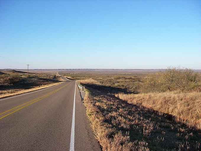 The highway rolls like ocean waves across the plains where shadows dance and the horizon seems impossibly far away.
