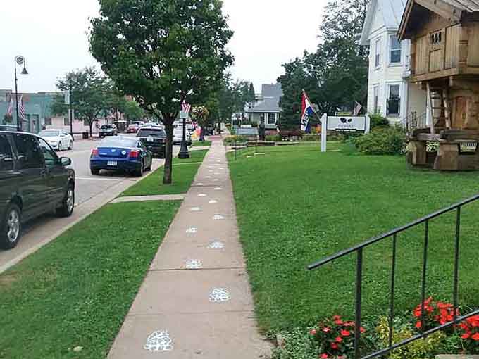 The sidewalk stretches invitingly past green lawns and historic homes, proving that sometimes one street is all you really need.