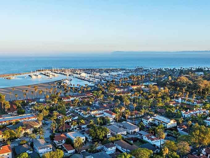 Red-tiled roofs and palm trees stretch toward the harbor where sailboats bob like a Mediterranean dream relocated to California.