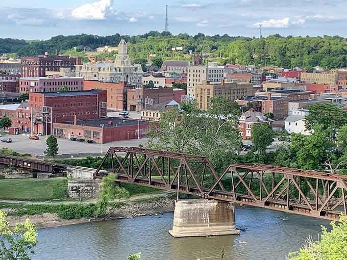 The river bridge frames a cityscape where brick buildings cluster together like old friends sharing stories across the water.