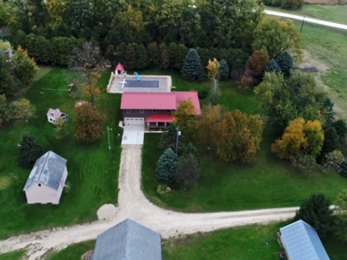 Tucked among trees with a red roof glowing in fall light, this Bellechester farmstead looks like a painting that wandered off the canvas.