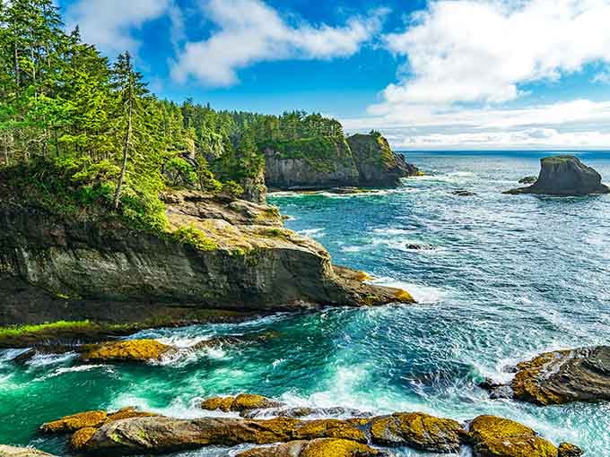 Turquoise waves carve caves into ancient rock formations that rise like natural cathedrals from the sea.