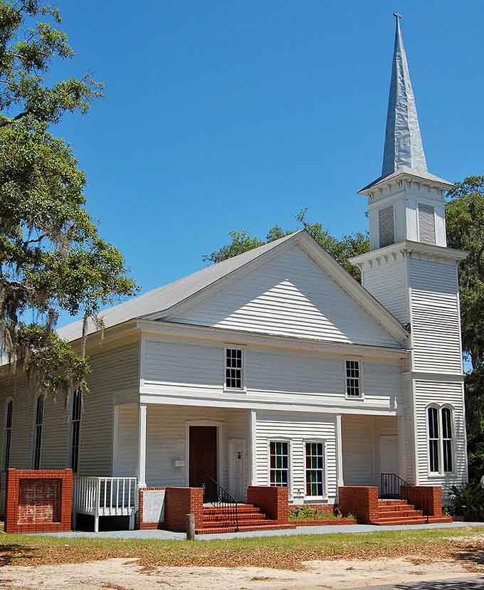 This pristine white church stands proud under blue skies, its steeple reaching heavenward like a postcard from simpler times.