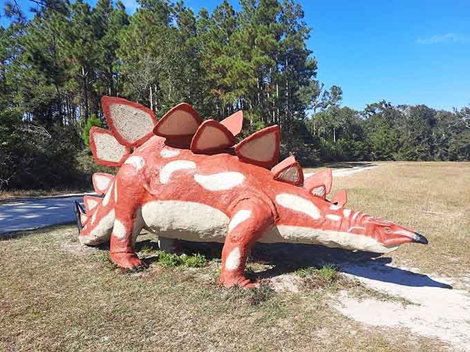 Bright orange plates line this stegosaurus's back, making it impossible to miss among the roadside greenery and trees.