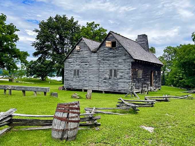 This weathered colonial building tells stories of centuries past while surrounded by split-rail fences and green lawns.