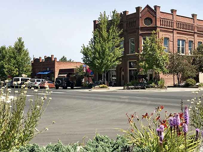 Wildflowers bloom in the foreground while historic brick buildings anchor this mountain town's main square.