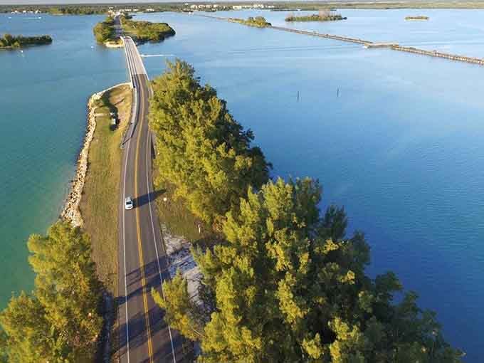 This aerial view shows the road threading through islands like a needle pulling thread through blue fabric.