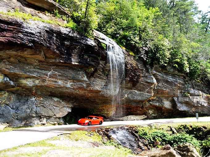 That bright orange sports car provides the perfect pop of color against layered rock and the gentle waterfall above.