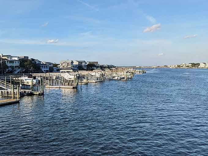 Boat docks line the calm waterway where houses perch along shores that shimmer in afternoon sunlight.
