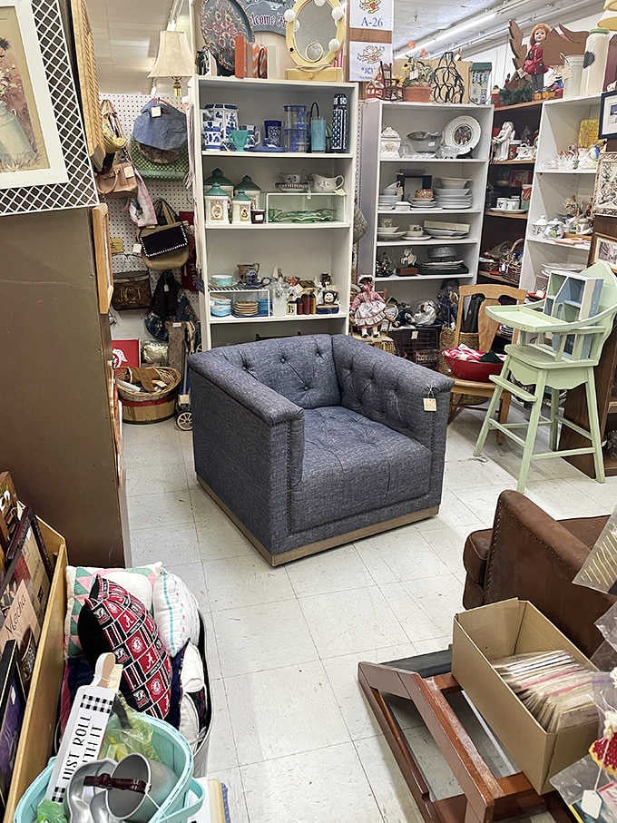 That tufted chair sits ready for its next home, surrounded by shelves of treasures begging for adoption.