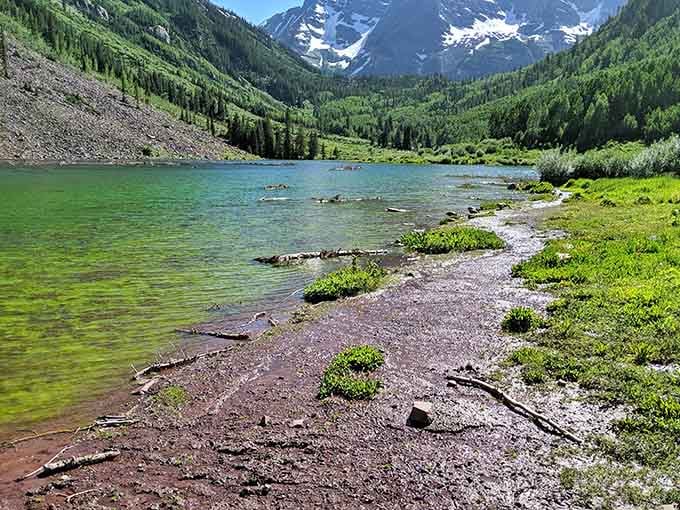 Maroon Bells reflects in crystal-clear water, creating the kind of symmetry that makes photographers weep with joy.