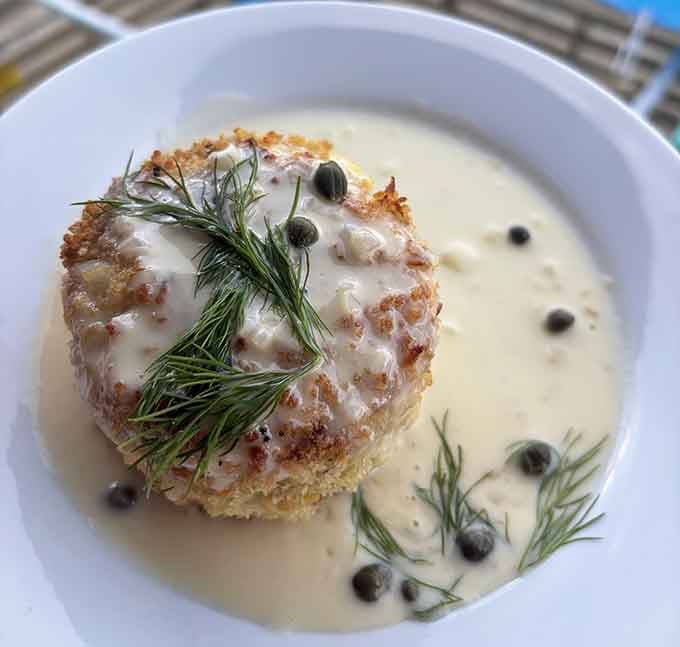 That golden crab cake sitting in creamy sauce looks fancier than most landlocked restaurants could ever dream of serving.