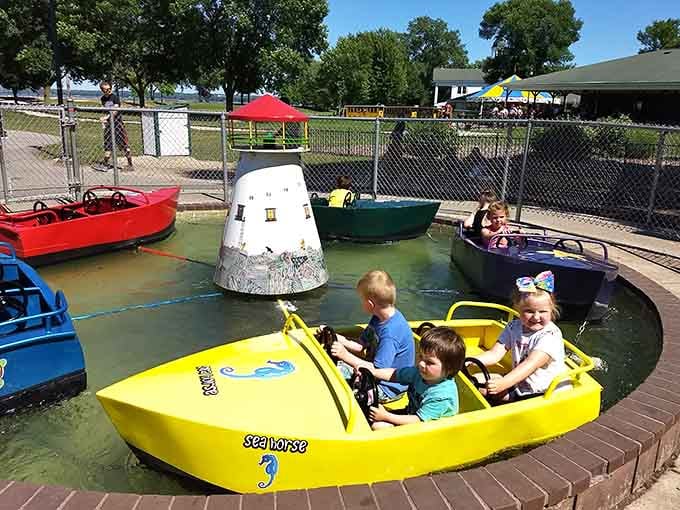 Young captains navigate their colorful vessels around the lighthouse, learning the ropes of maritime adventure one lap at a time.