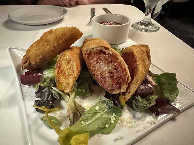 Golden-fried Italian eggrolls sitting pretty on fresh greens, because sometimes fusion food just makes sense in the best possible way.