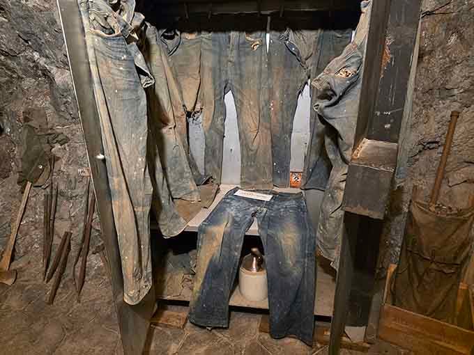 Authentic miner clothing hangs ready for the next shift, a haunting reminder of the tough souls who worked here.