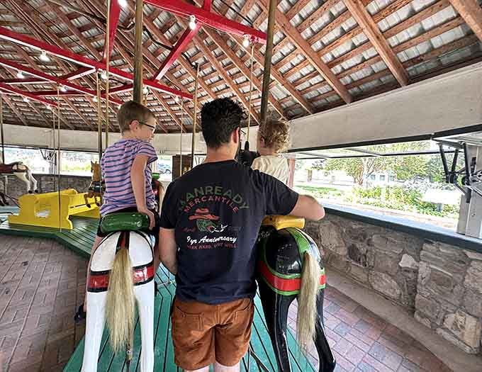 Dad duty at its finest: lifting kids onto carousel horses while pretending you're not excited too.