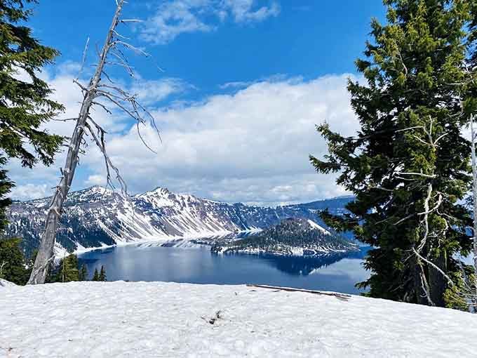 Winter transforms the caldera into a snow-globe scene where blue water meets endless white in stunning contrast.