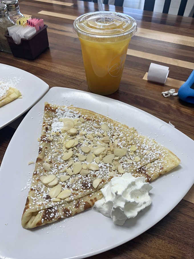 Sliced almonds scattered over a sweet crepe with whipped cream, like edible confetti celebrating your excellent breakfast choice.