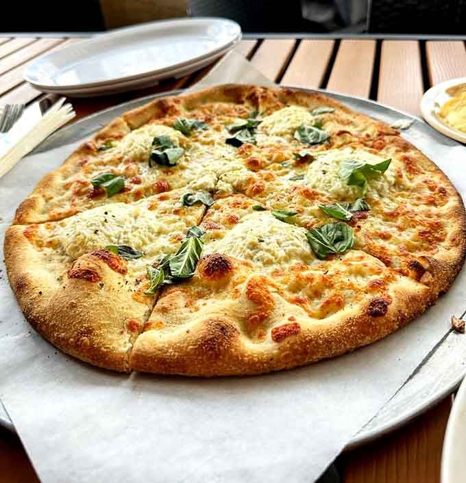 Fresh basil tops this pizza like little flavor grenades waiting to explode in your mouth with every slice.