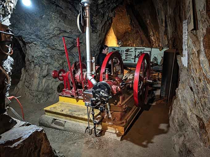 Vintage machinery with red wheels once powered the operation, turning human sweat into mechanical advantage one crank at a time.