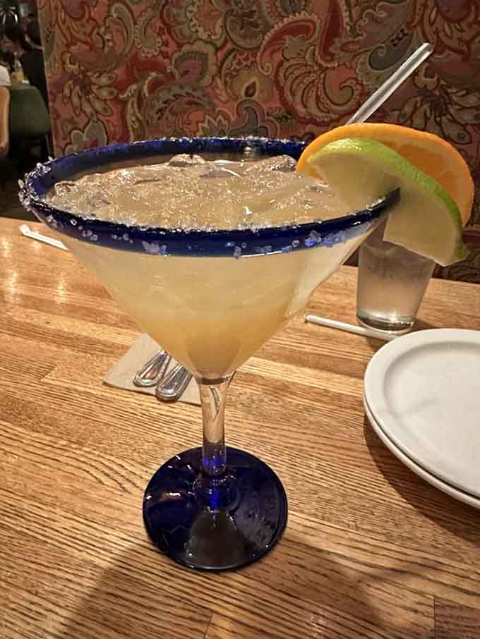 That blue-rimmed margarita glass holds liquid sunshine with just enough salt to keep things interesting.